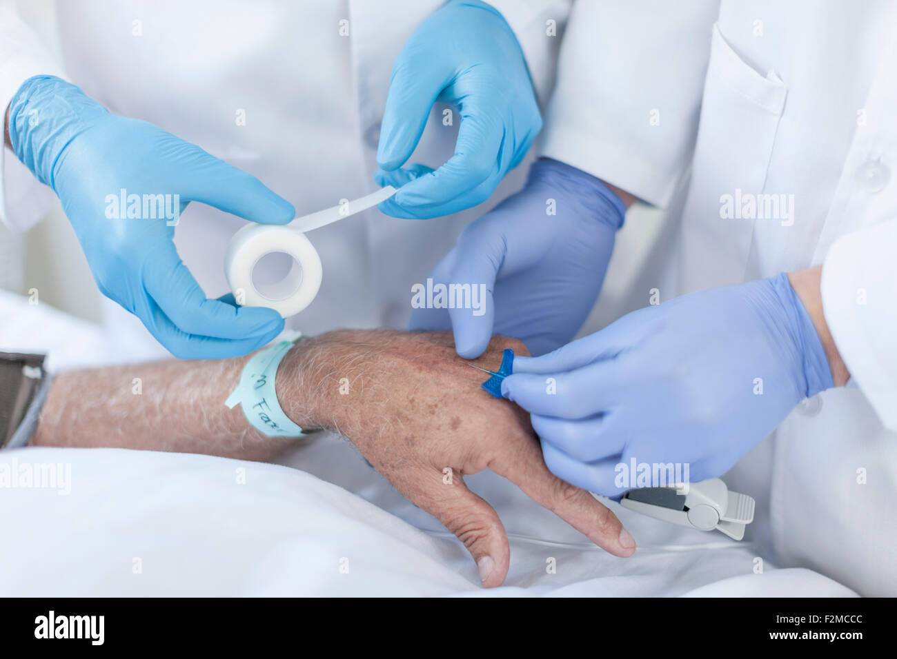 Nurse inserting IV needle in patients hand Stock Photo - Alamy