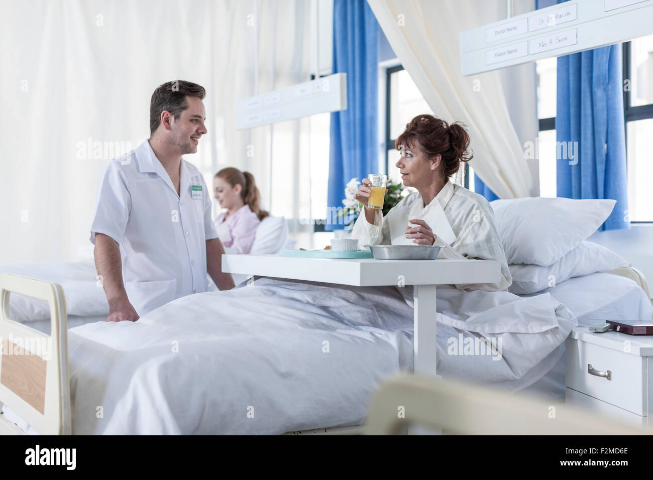 Nurse looking at patient drinking juice Stock Photo - Alamy