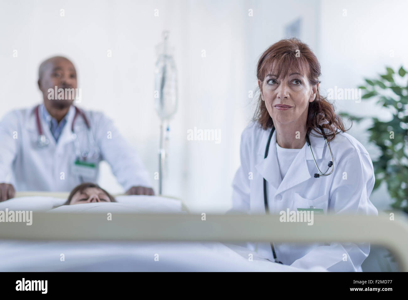 Two doctors pushing hospital bed with patient Stock Photo - Alamy