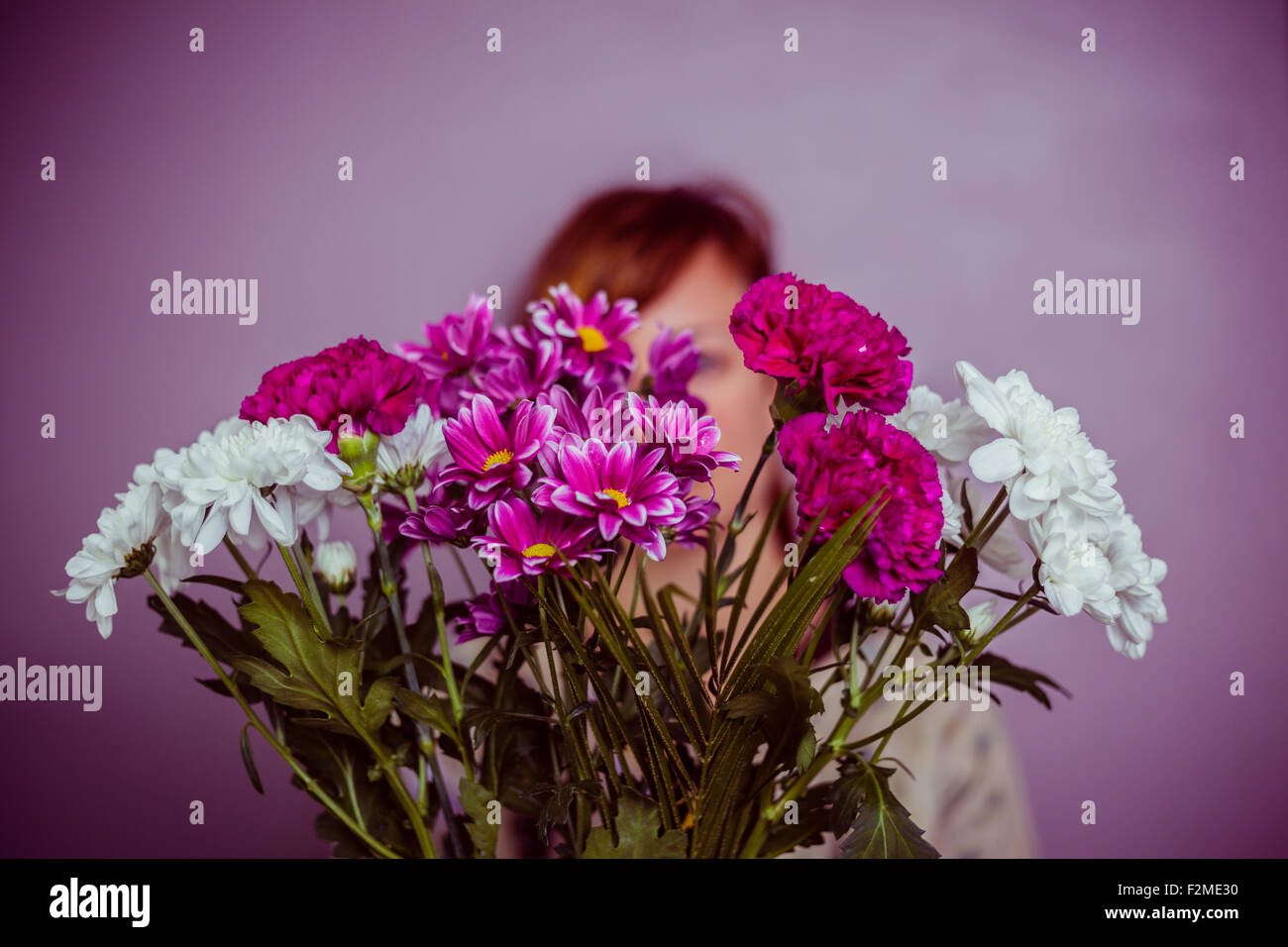 Young woman hiding behind bouquet of flowers Stock Photo - Alamy