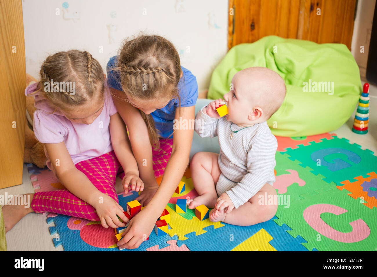 Happy kids playing with little brother in the room Stock Photo - Alamy