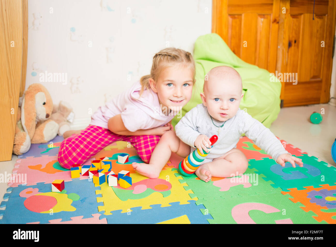 Happy kids playing with little brother in the room Stock Photo - Alamy