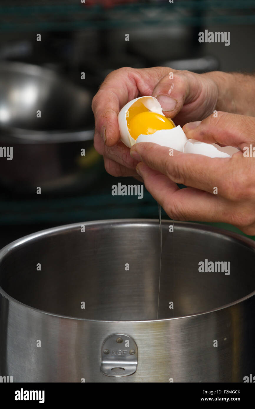 close up of a chefs hands separating the egg yolk form the white by hand Stock Photo - Alamy