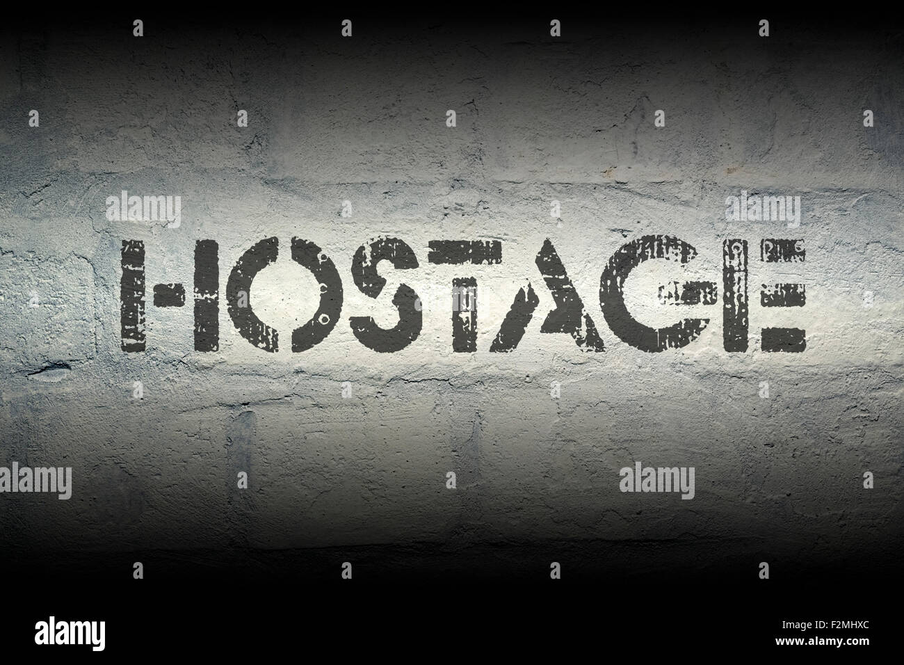 hostage stencil print on the grunge white brick wall Stock Photo - Alamy