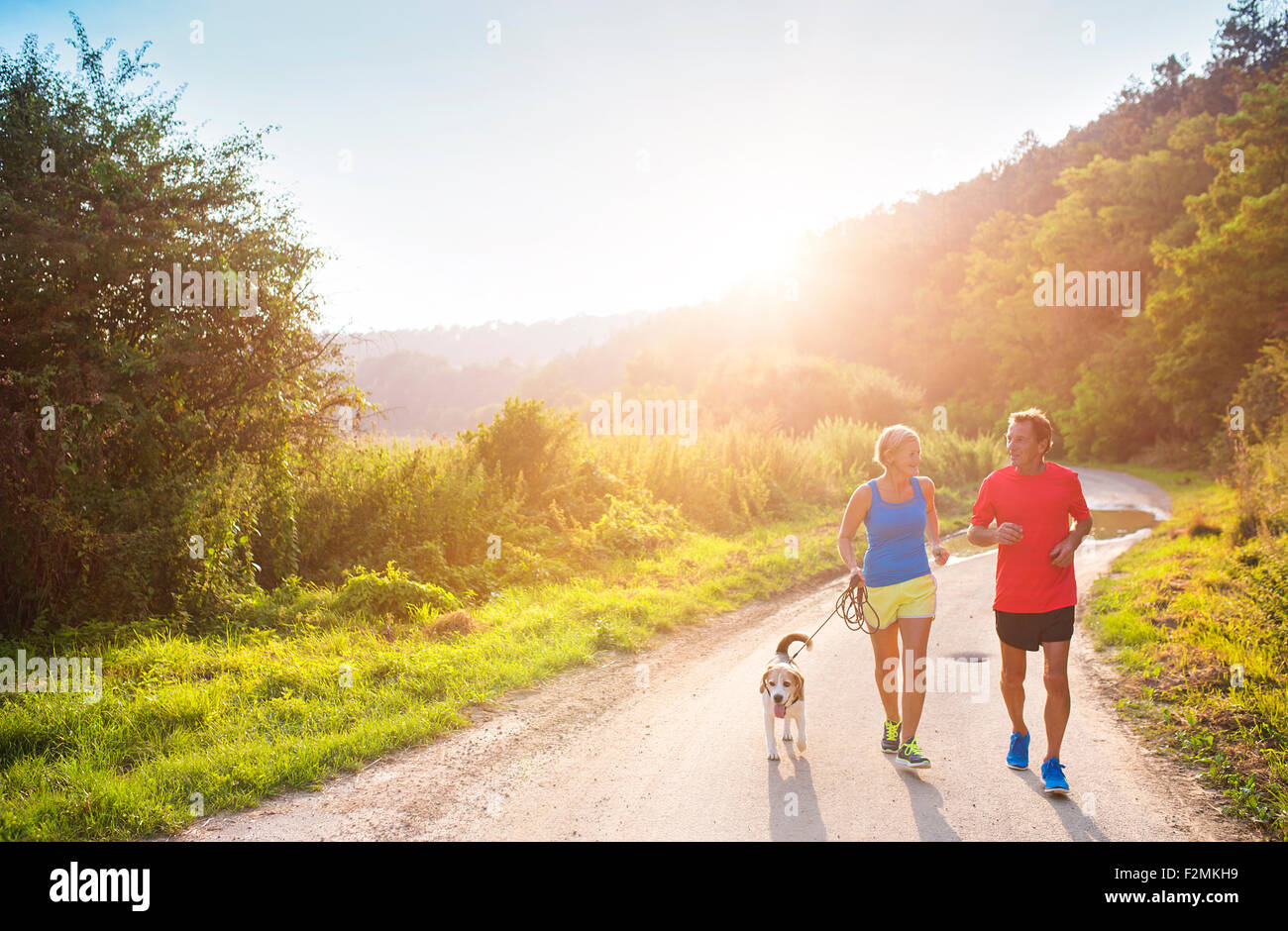 Active seniors running with their dog outside in green nature Stock ...