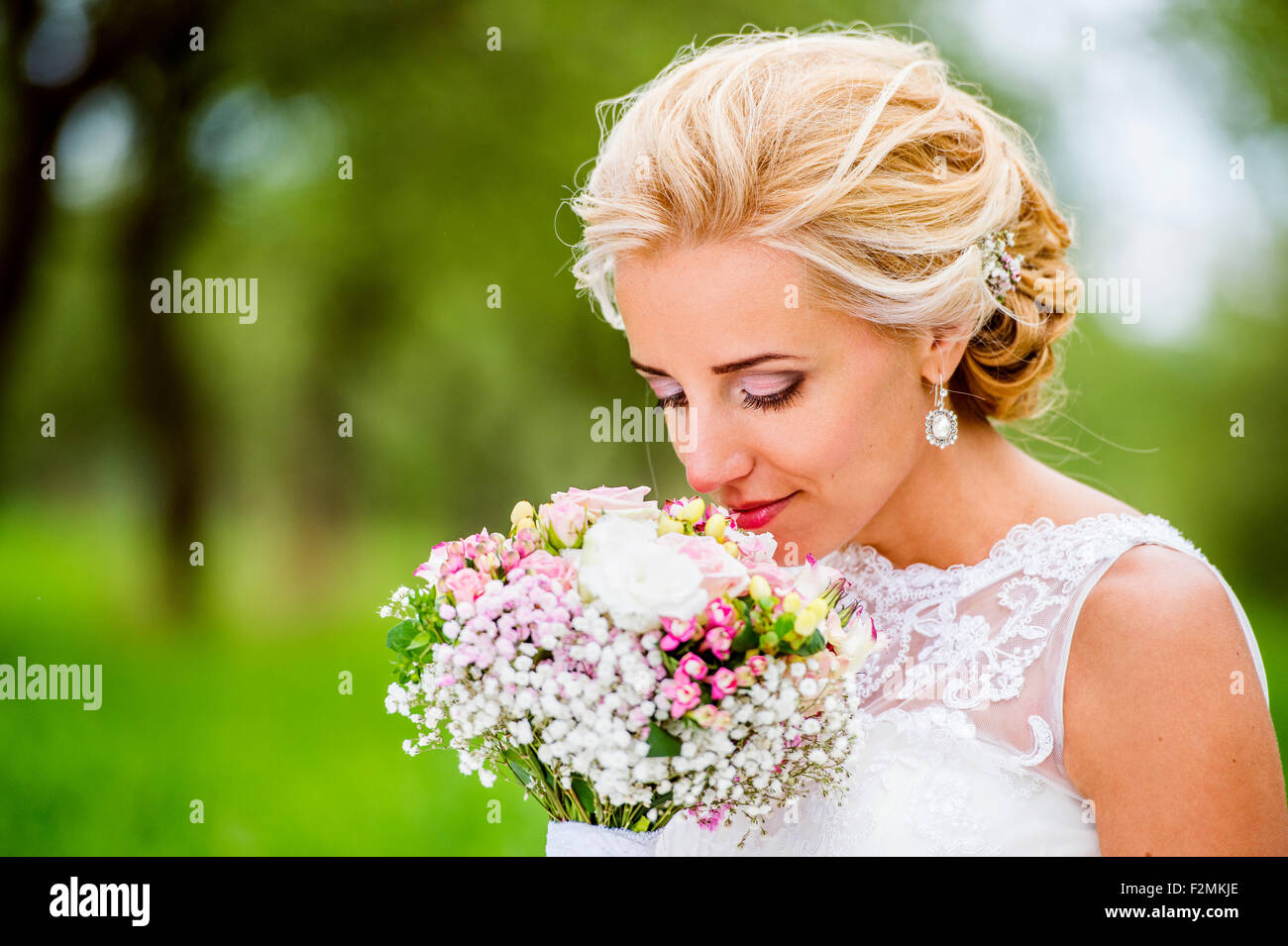 Beautiful young bride in wedding dress sitting in the grass Stock Photo ...