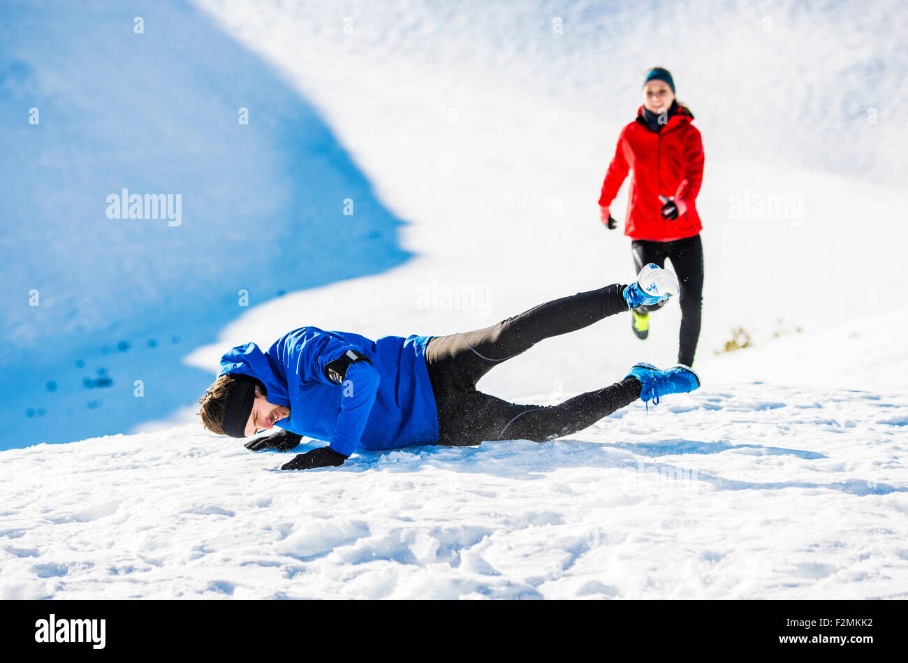 Young man falling while jogging outside in sunny winter mountains Stock ...
