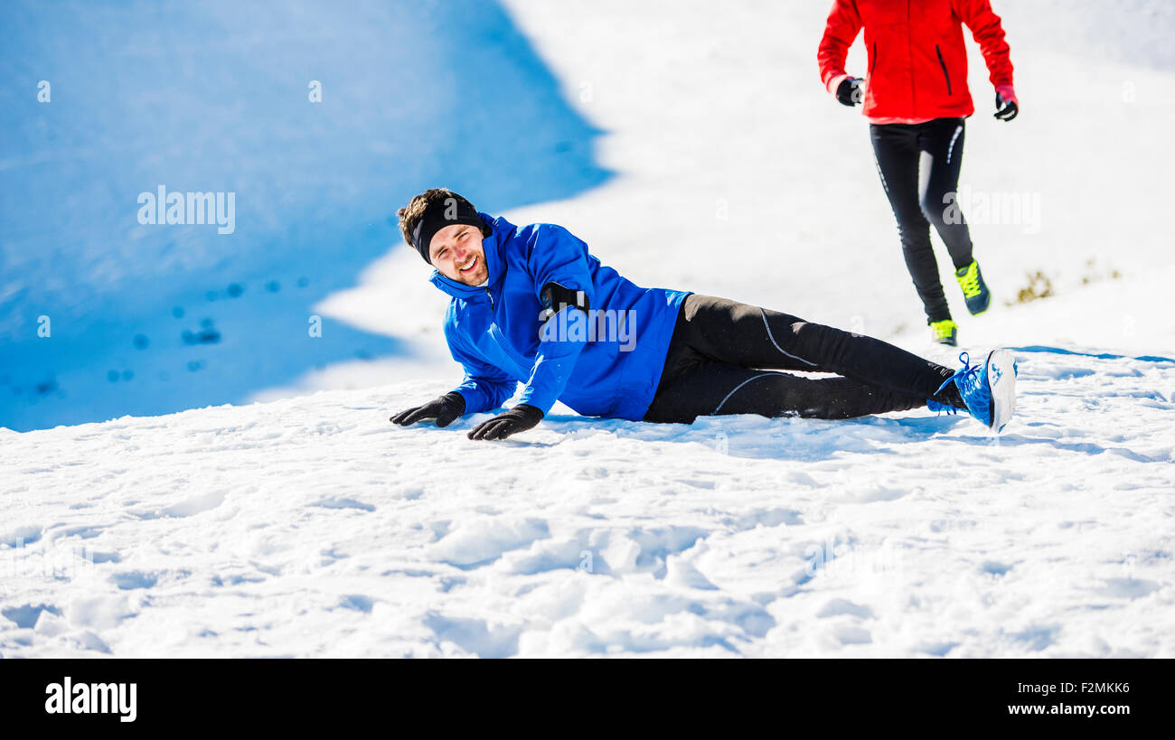 Young man falling while jogging outside in sunny winter mountains Stock ...
