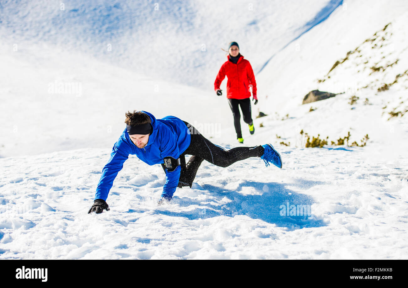 Young man falling while jogging outside in sunny winter mountains Stock ...