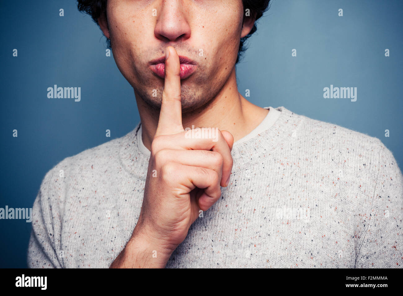 Young man with finger on his lips Stock Photo - Alamy