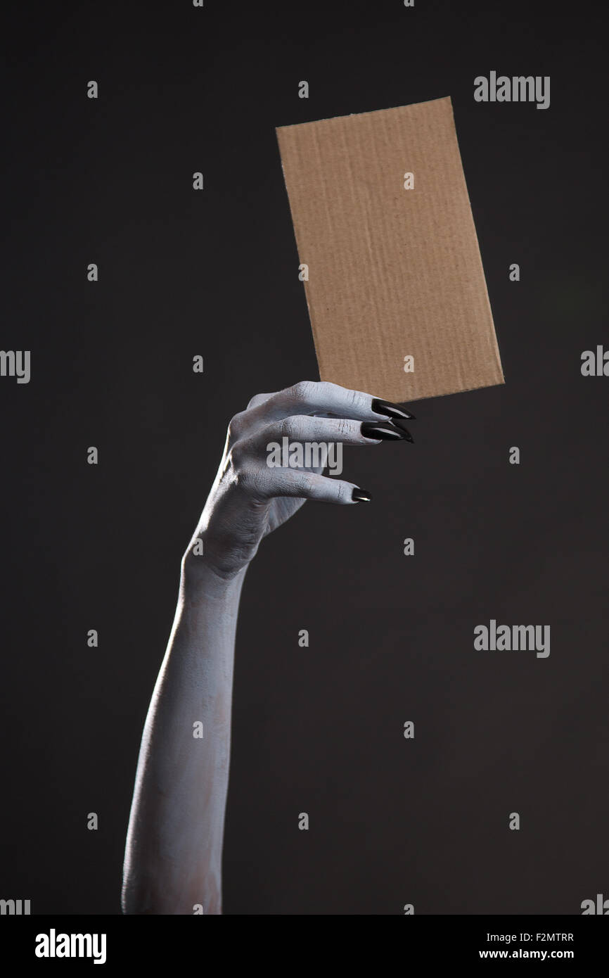White ghost or witch hand with black nails holding blank cardboard ...