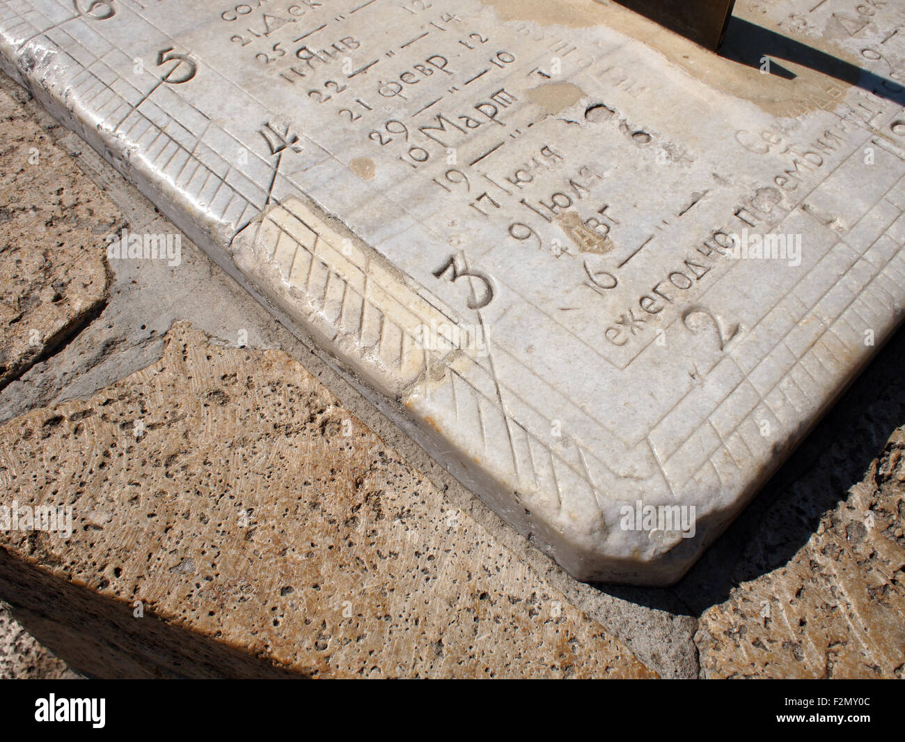 Detail of ancient stone dial sundial closeup. On the white marble slab ...
