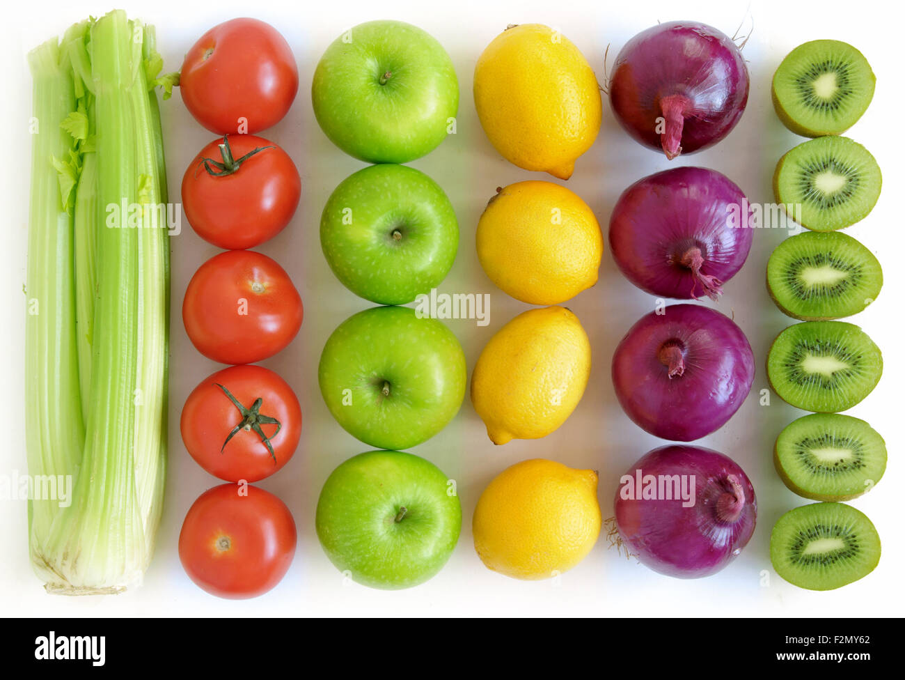 Colorful assortment of fruits and vegetables in rows over a white ...