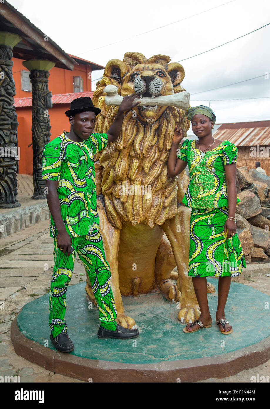 Benin, West Africa, Savalou, couple pausing in front of a lion statue ...