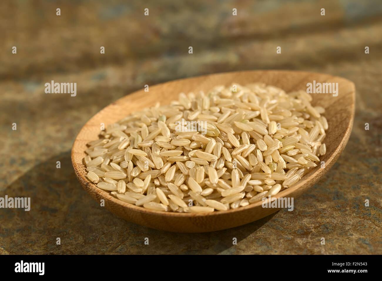 Raw brown or wholegrain rice kernels on small plate, photographed on ...