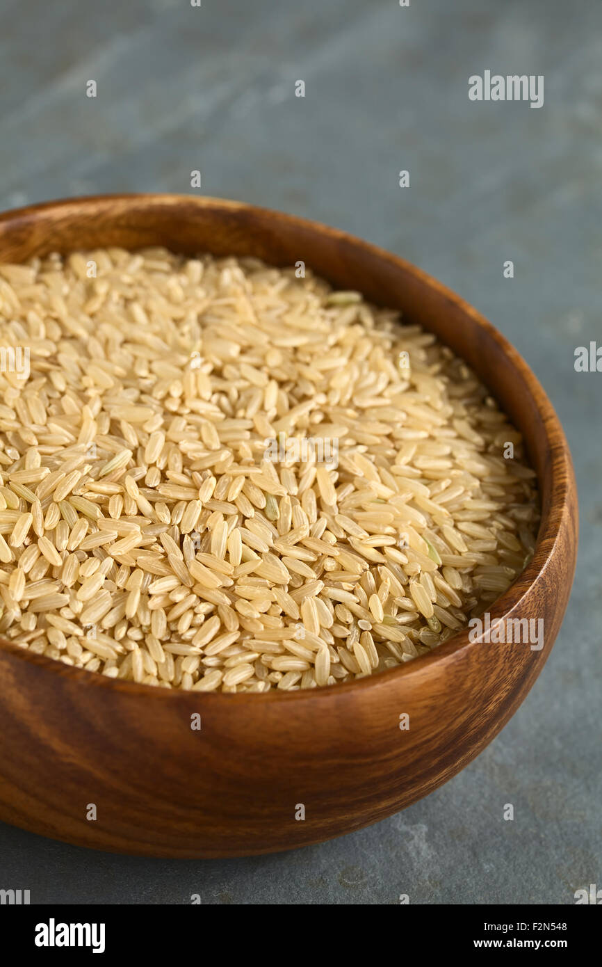 Raw brown or wholegrain rice kernels in wooden bowl, photographed on ...