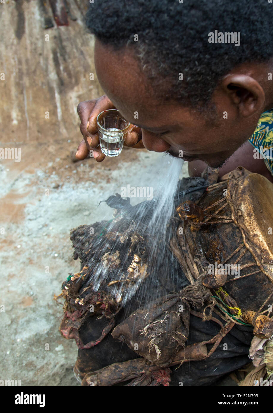 Benin, West Africa, Bopa, drummer spitting alcohol on a drum to wake up ...
