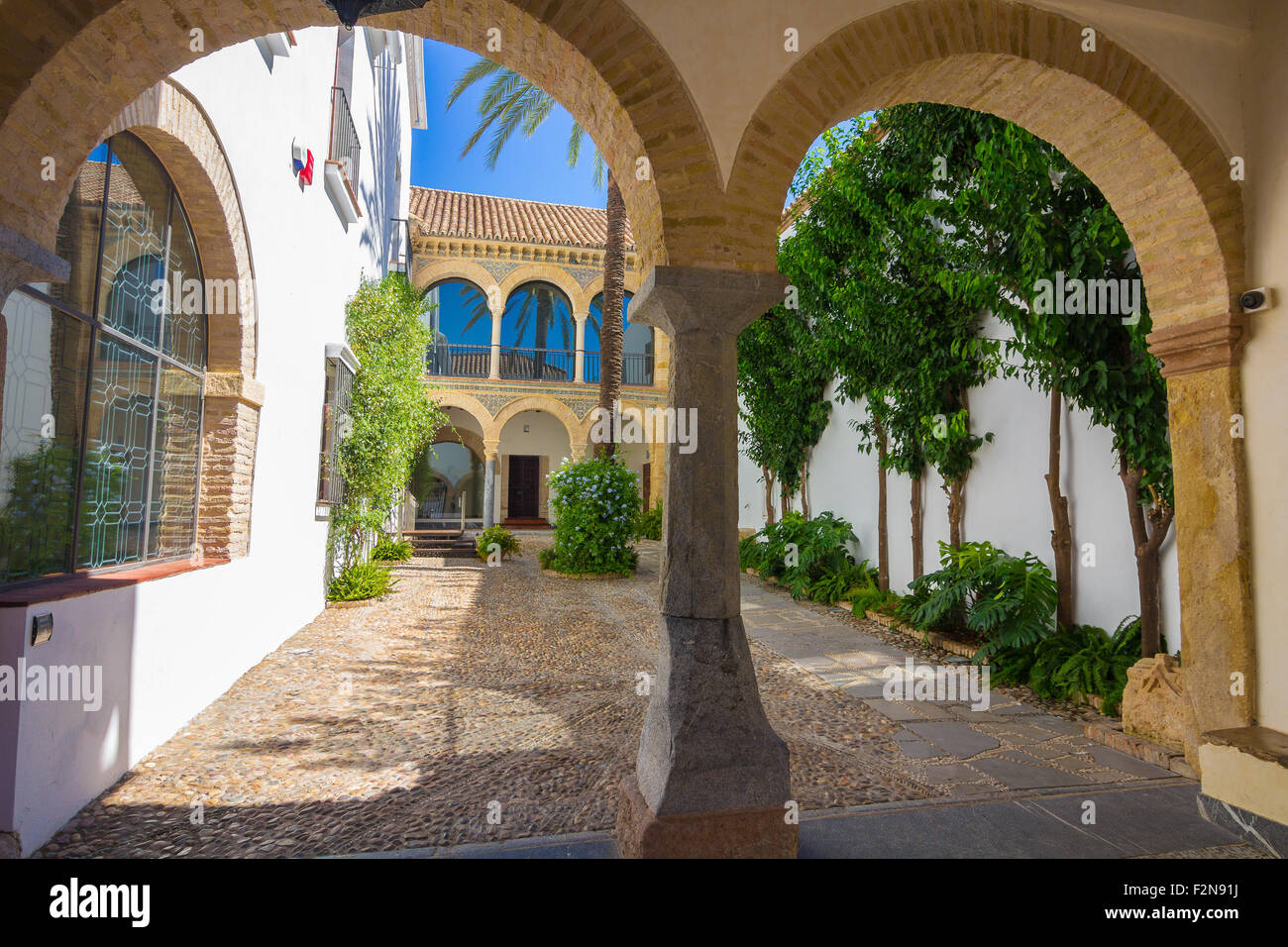 typical Andalusian courtyard decorated with flowers arches and columns ...