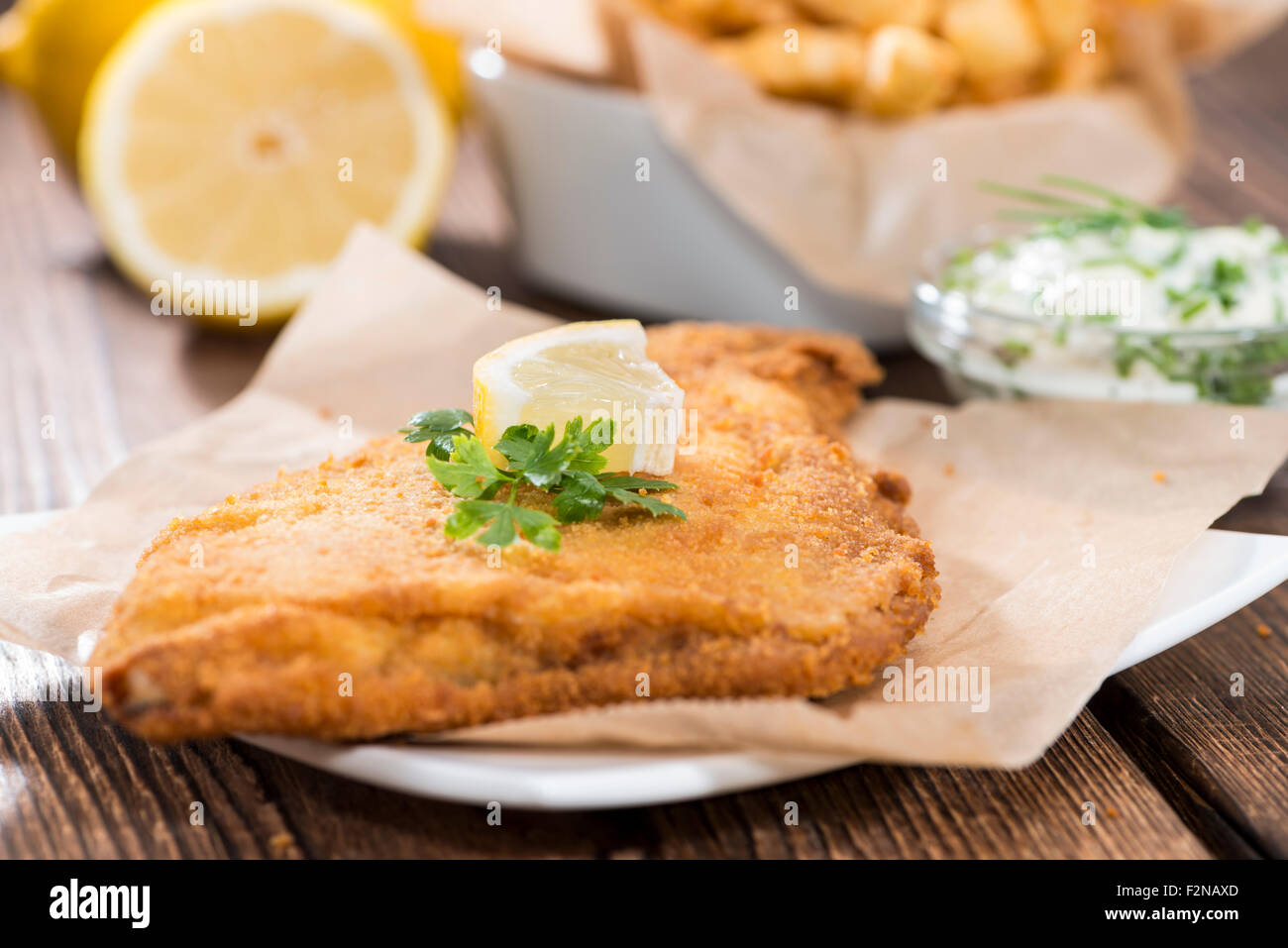 Fried Plaice with french fries (close-up shot) on wooden background ...