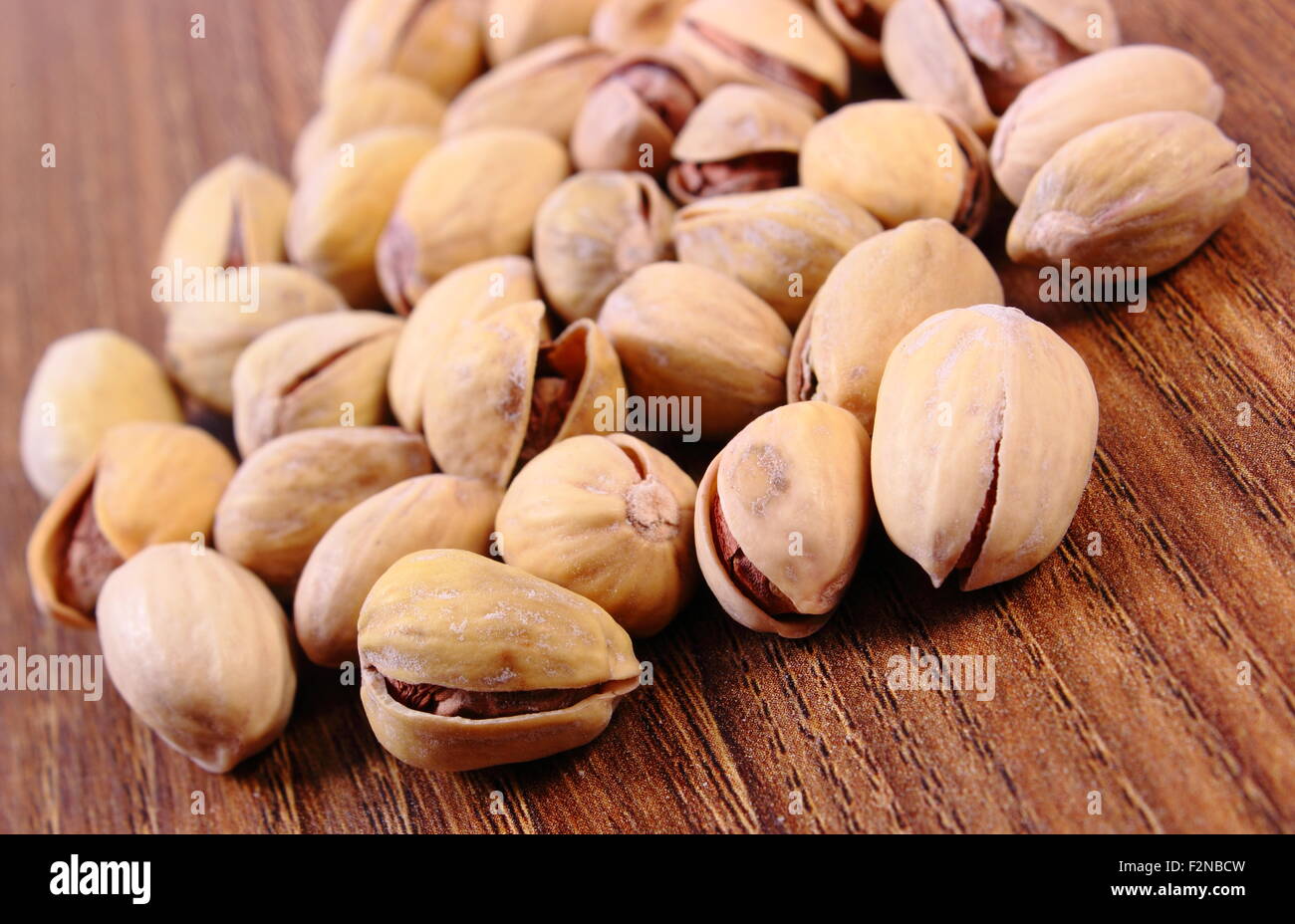 Roasted pistachio nuts on natural wooden table background, healthy food and nutrition Stock ...