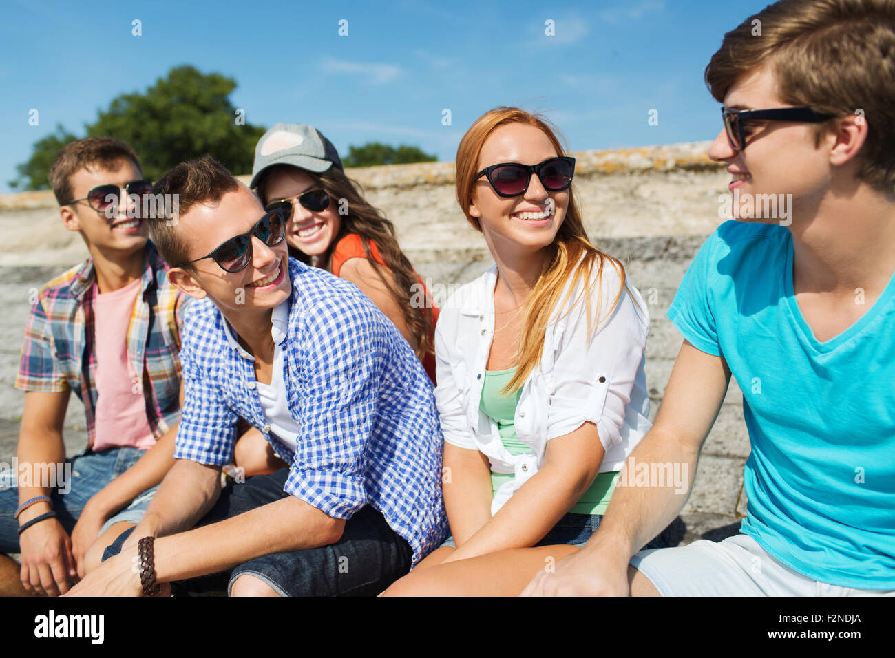 group of smiling friends sitting on city street Stock Photo - Alamy