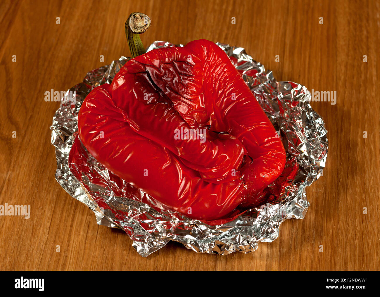 Fried red pepper vegetable in foil on wood table Stock Photo - Alamy