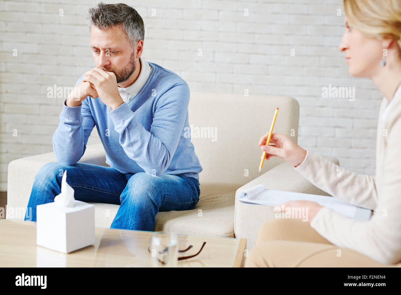 Sad man sitting by his psychologist Stock Photo - Alamy