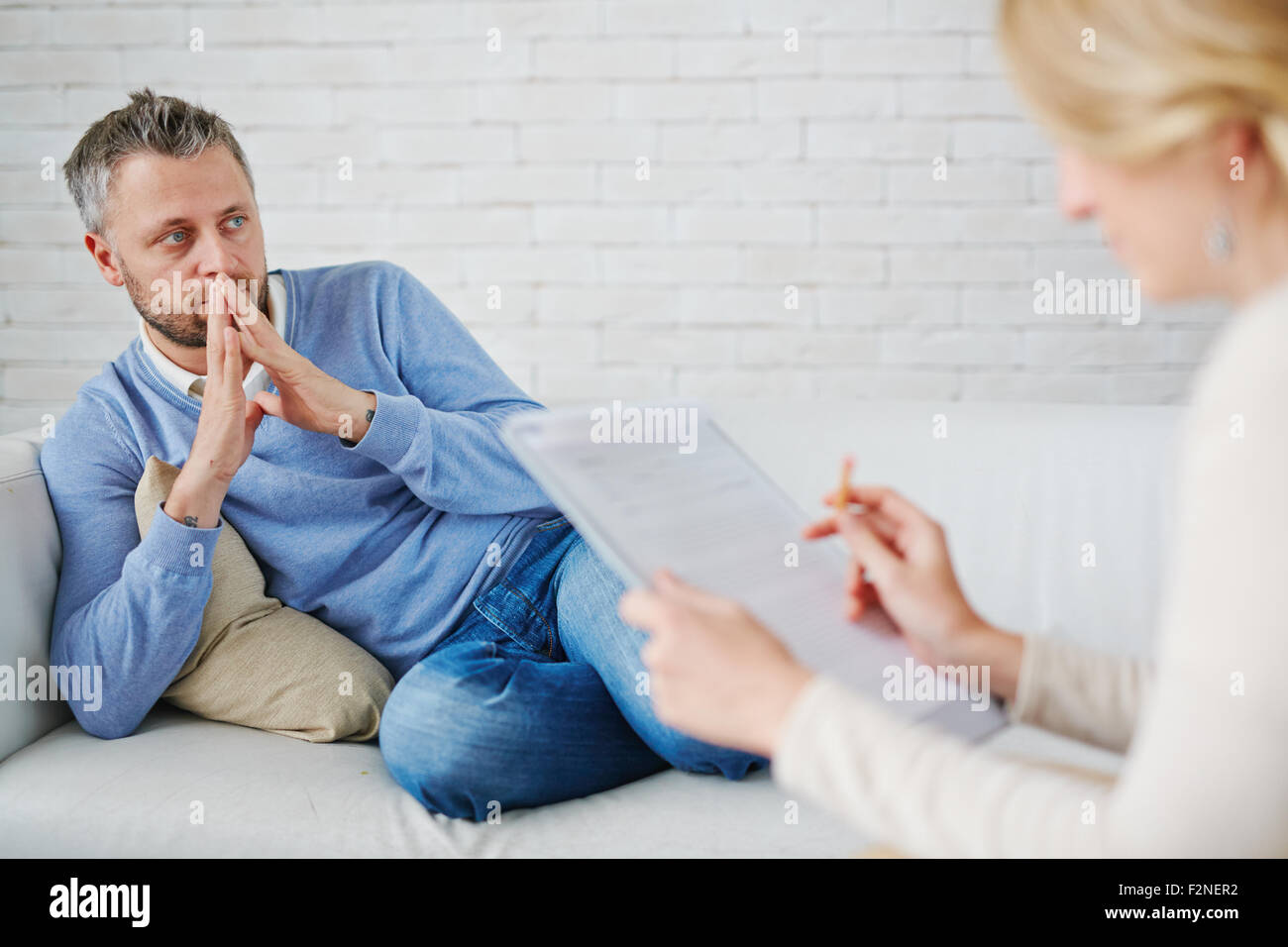 Thoughtful man sitting on sofa in front of his psychologist Stock Photo ...