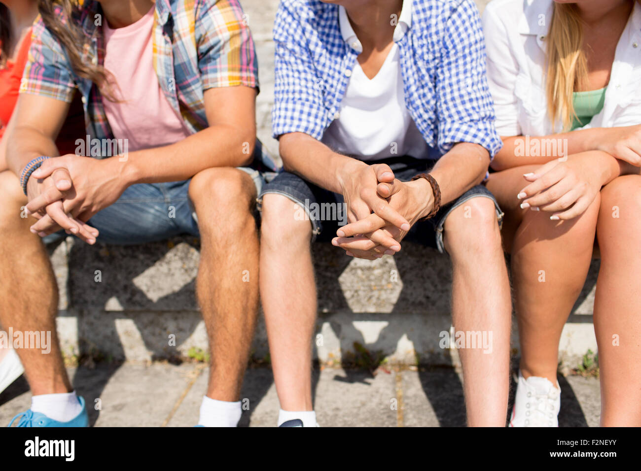 close up of friends legs sitting on city square Stock Photo - Alamy