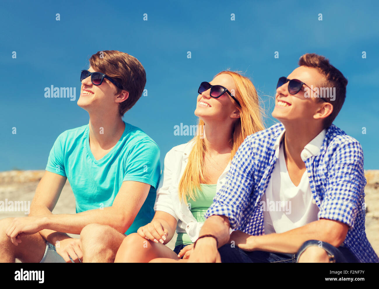 group of smiling friends sitting on city street Stock Photo - Alamy