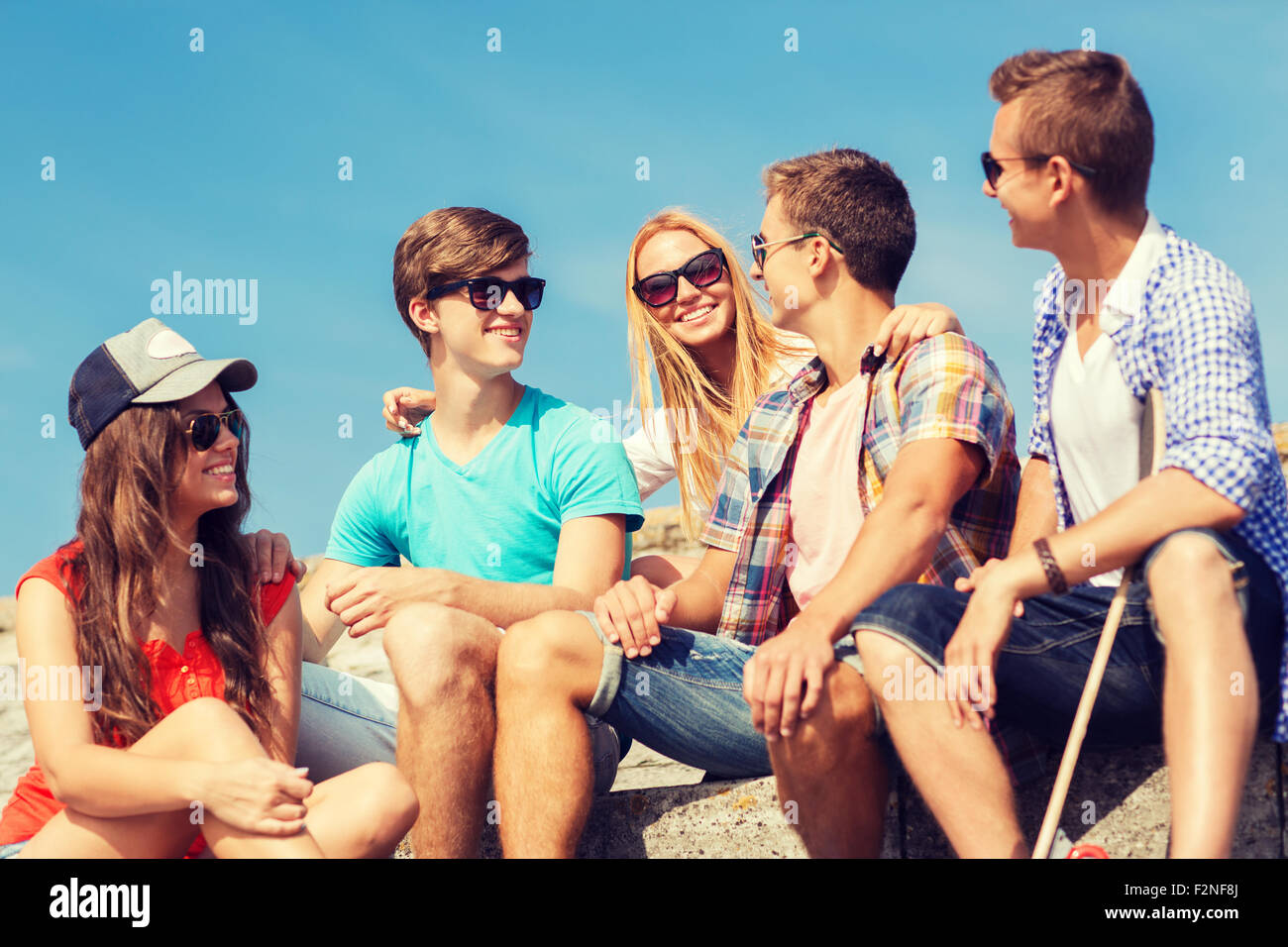 group of smiling friends sitting on city street Stock Photo - Alamy