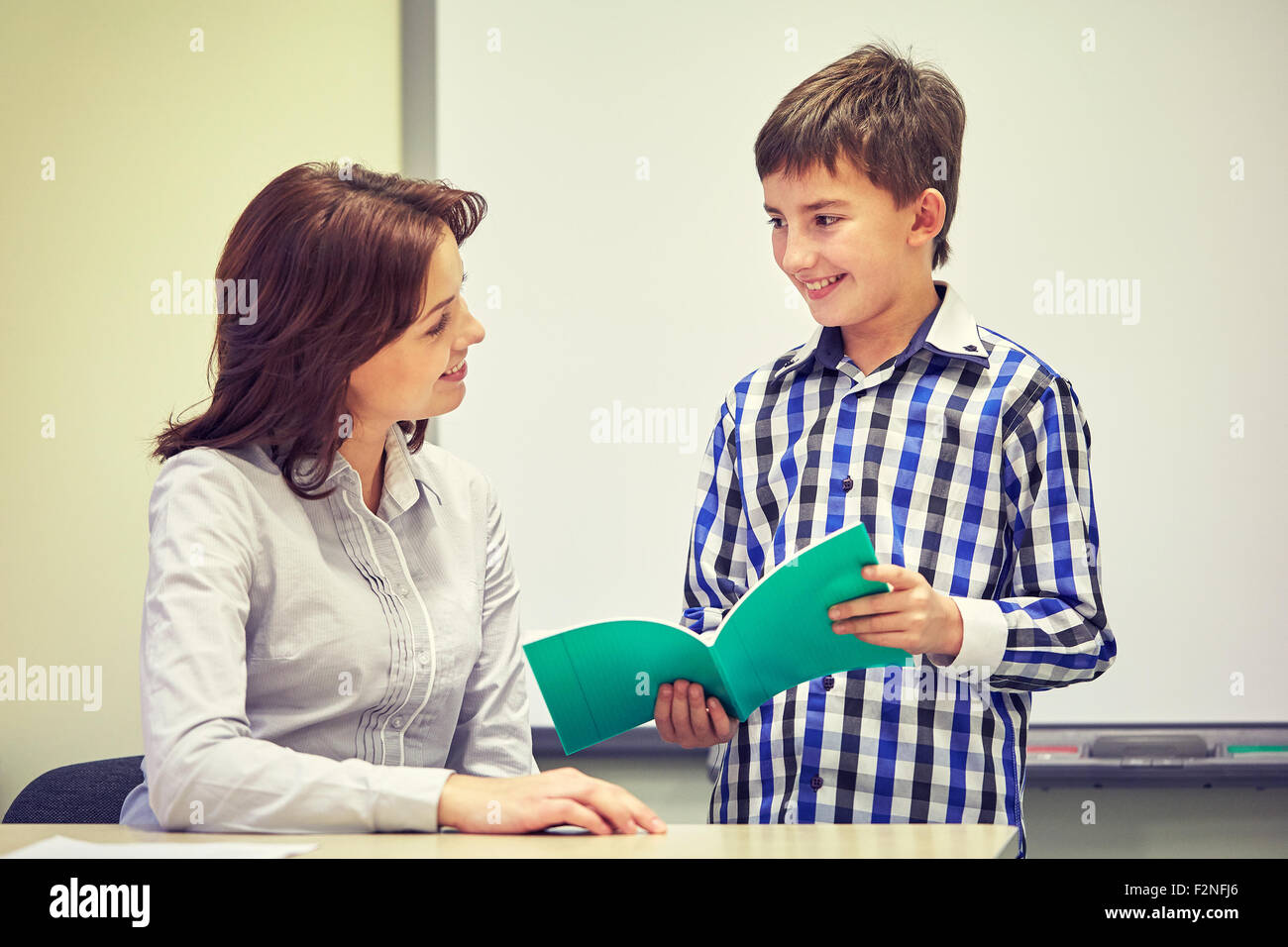 school boy with notebook and teacher in classroom Stock Photo - Alamy