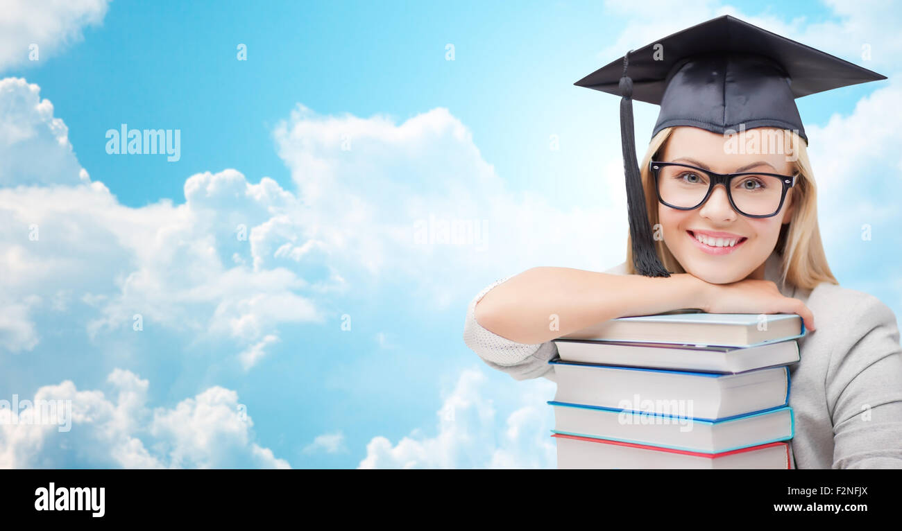 student in trencher cap with books over blue sky Stock Photo - Alamy