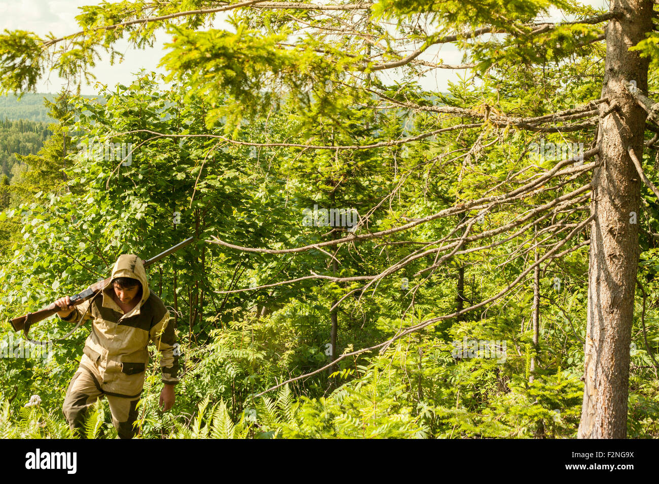 Mari man with gun climbing forest hill Stock Photo - Alamy