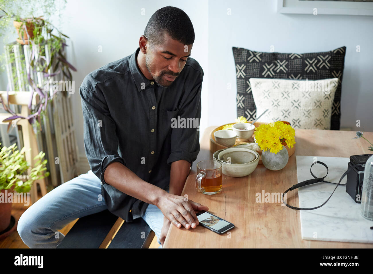 Black man using cell phone at table Stock Photo - Alamy