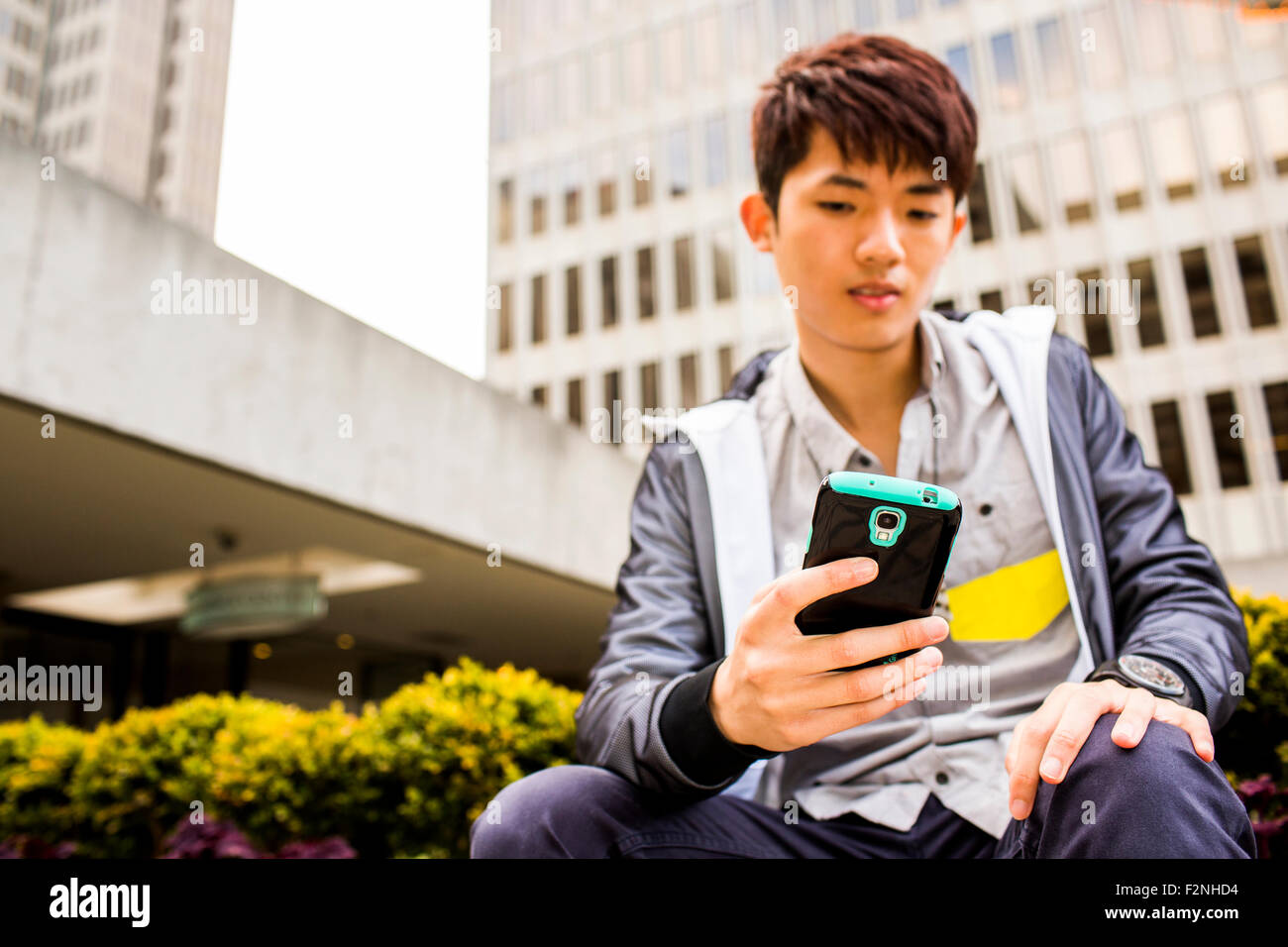 Asian man using cell phone in city Stock Photo - Alamy