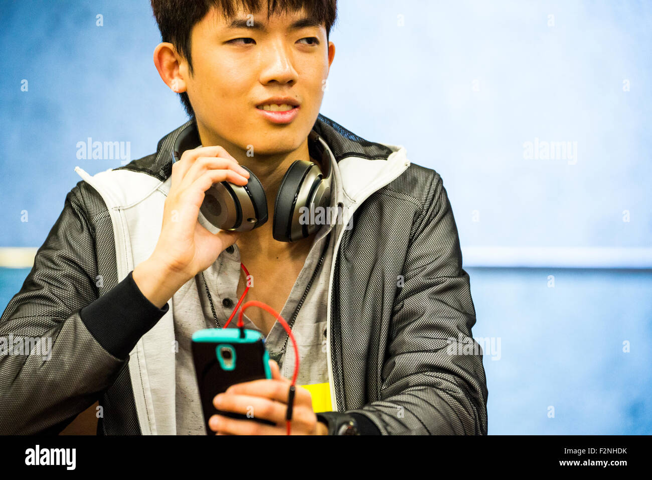 Asian man with headphone using cell phone Stock Photo - Alamy