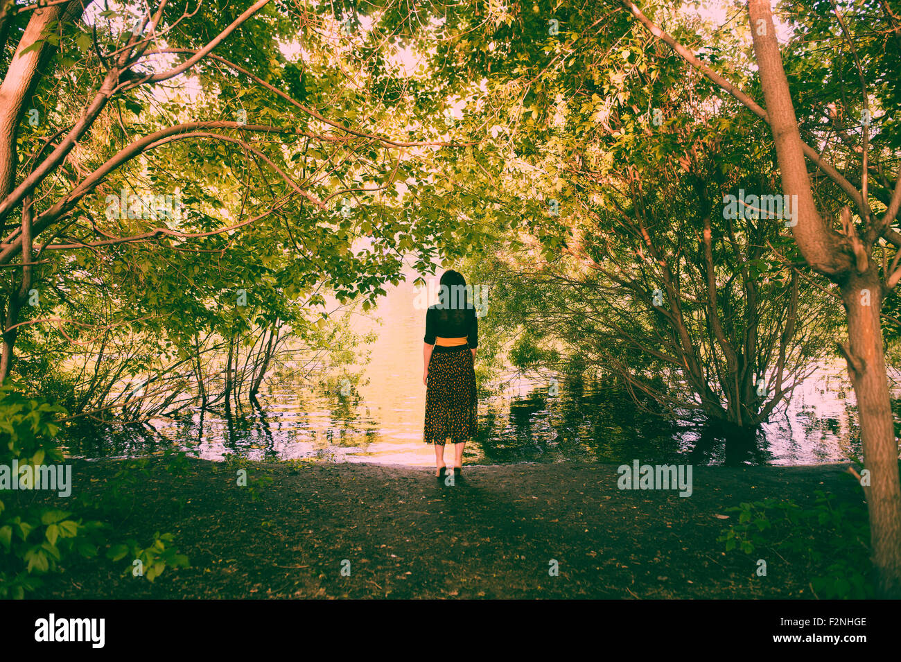 Caucasian woman standing under trees near river Stock Photo - Alamy