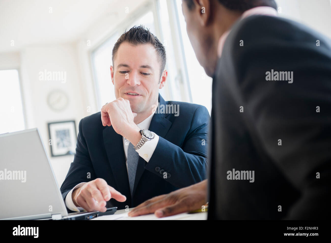 Businessmen talking at desk in office Stock Photo - Alamy