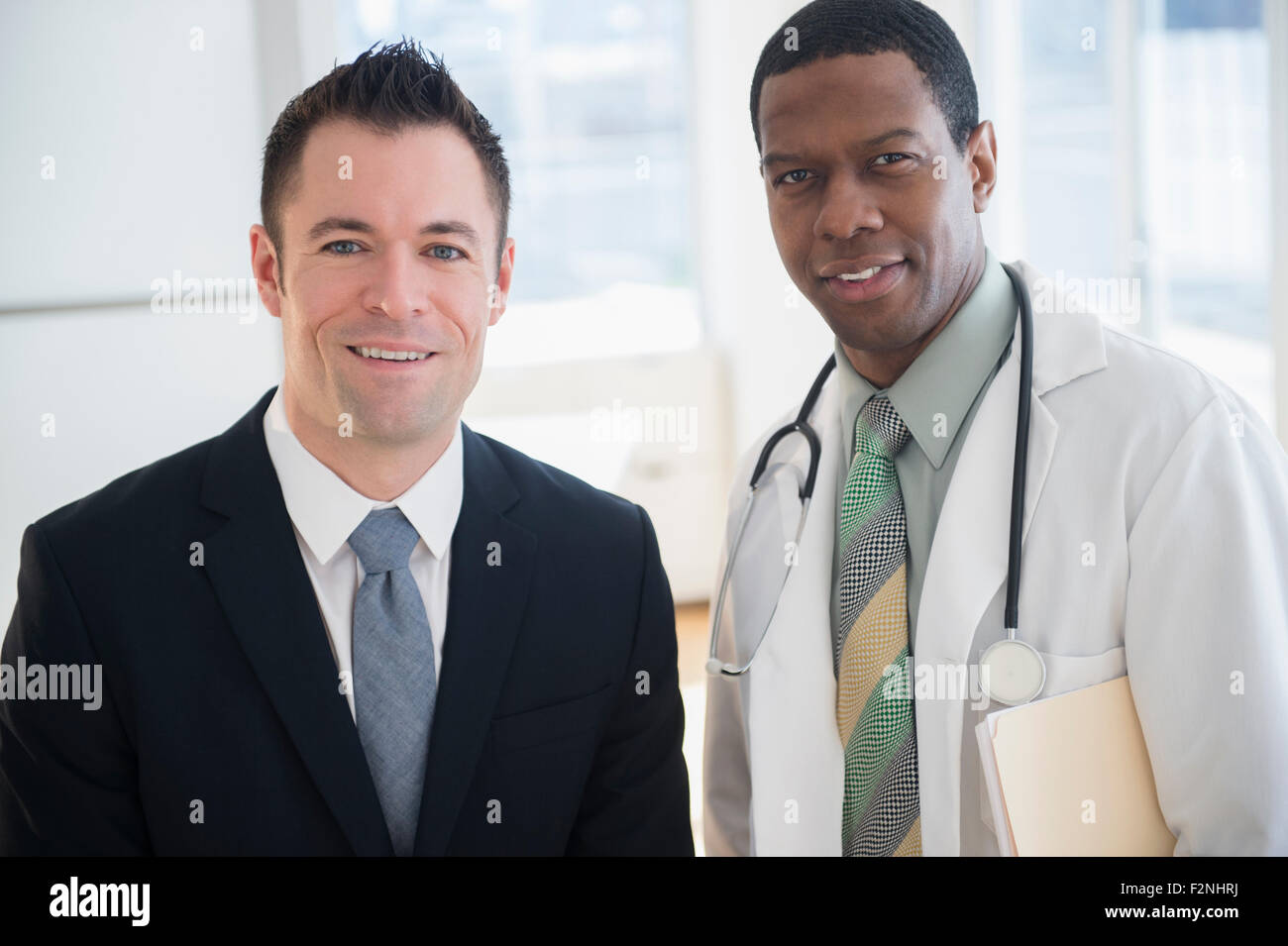 Businessman and doctor smiling in office Stock Photo - Alamy