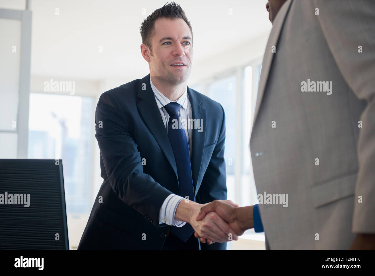 Two businessmen shaking hands at desk in the office Stock Photo - Alamy