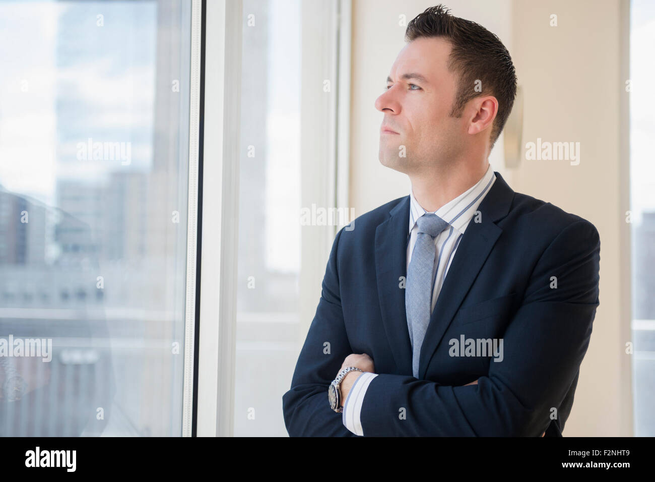 Businessman looking out office window Stock Photo - Alamy