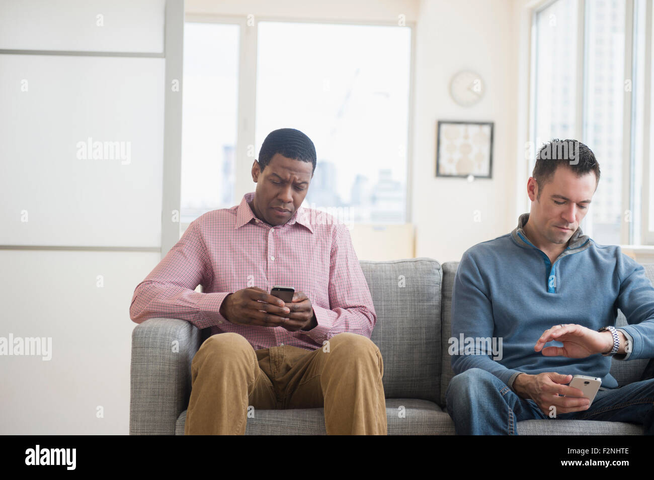 Men with cell phones waiting on sofa Stock Photo - Alamy