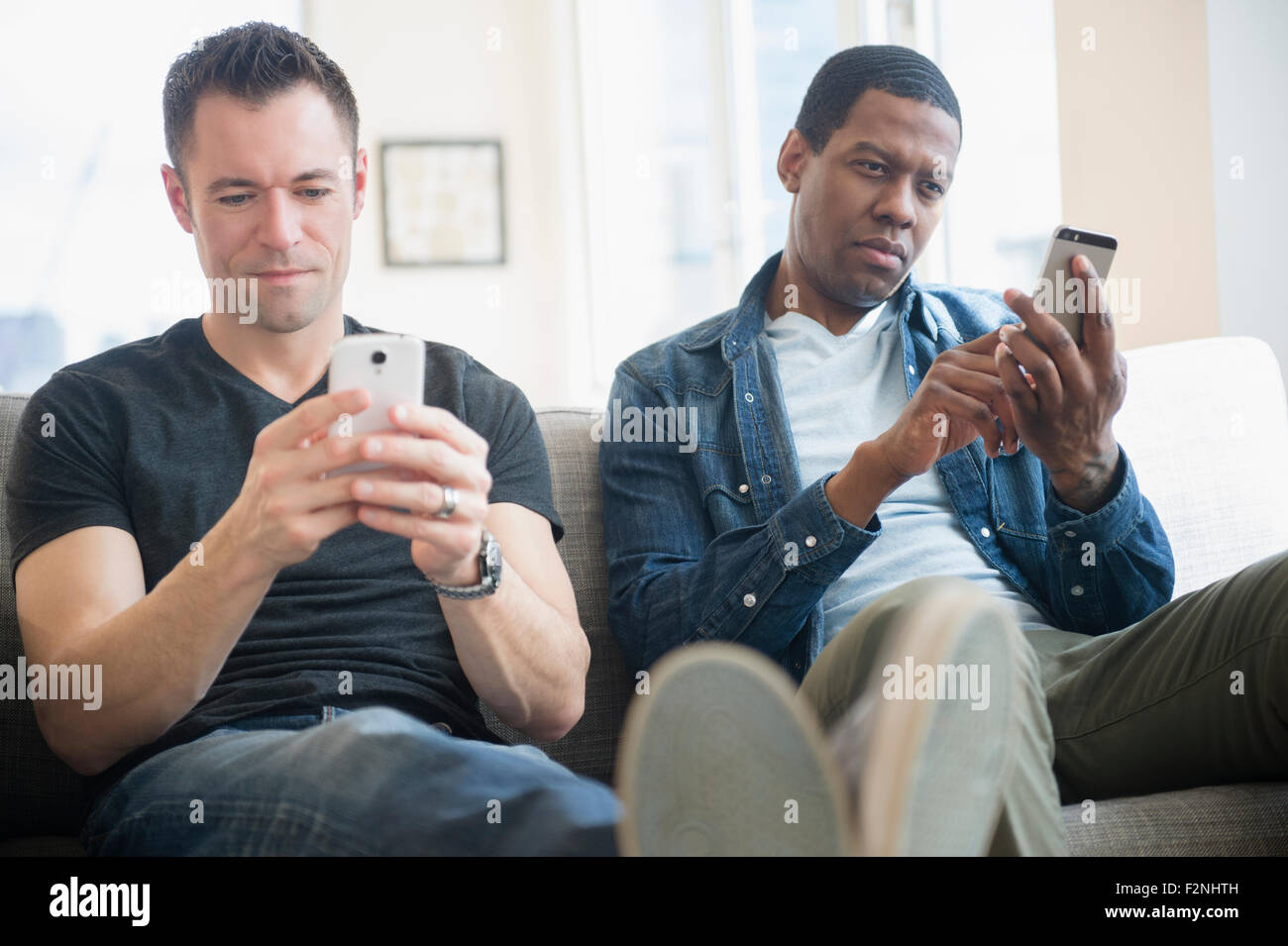 Men using cell phones on sofa Stock Photo - Alamy