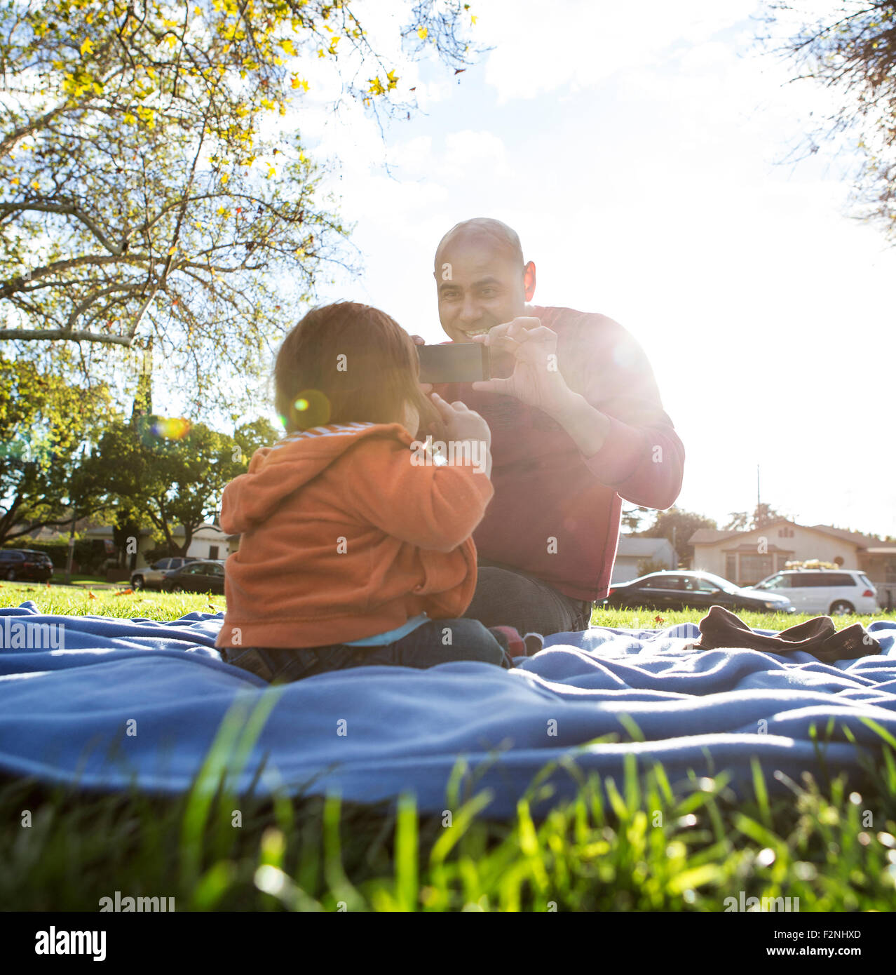 Hispanic father photographing son on blanket in park Stock Photo - Alamy