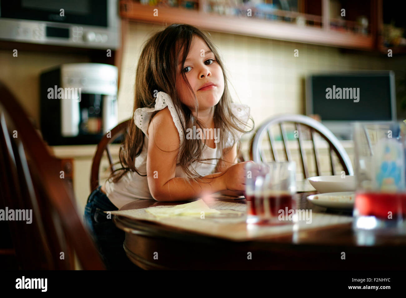 Caucasian girl eating at kitchen table Stock Photo - Alamy