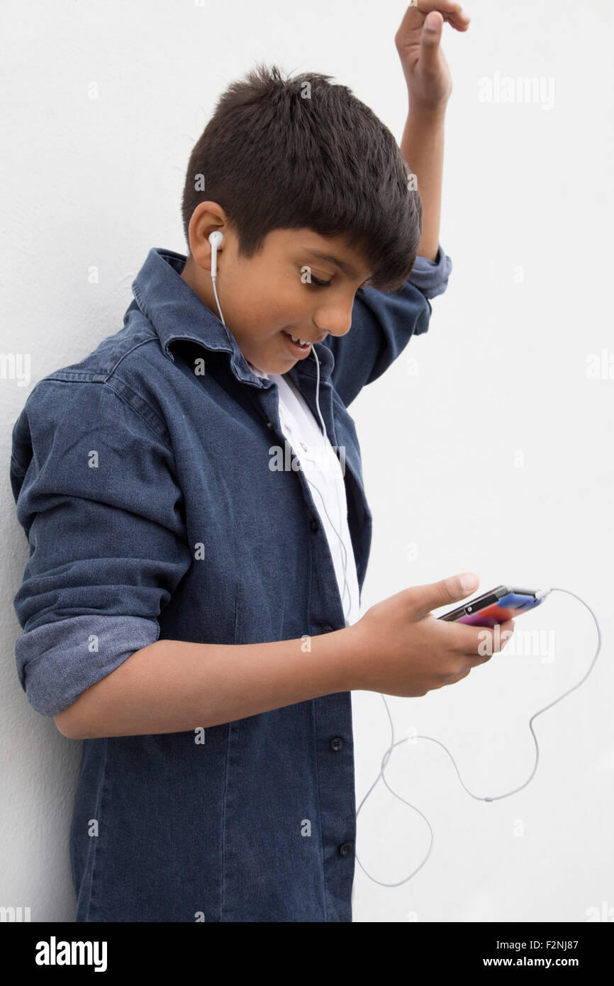 Asian boy listening to earbuds with cell phone Stock Photo - Alamy