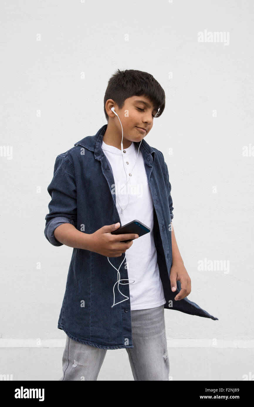 Asian boy listening to earbuds with cell phone Stock Photo - Alamy