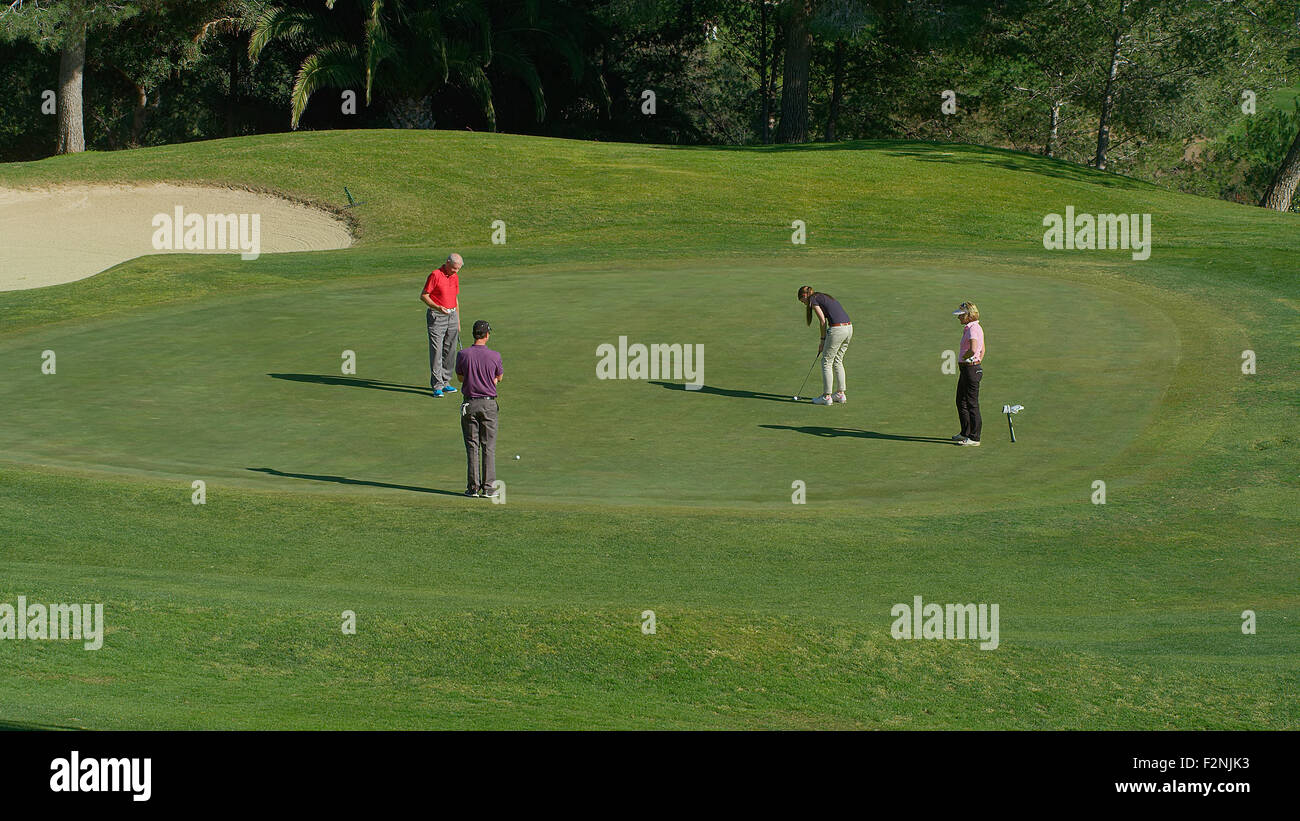 Caucasian friends putting on golf course Stock Photo - Alamy