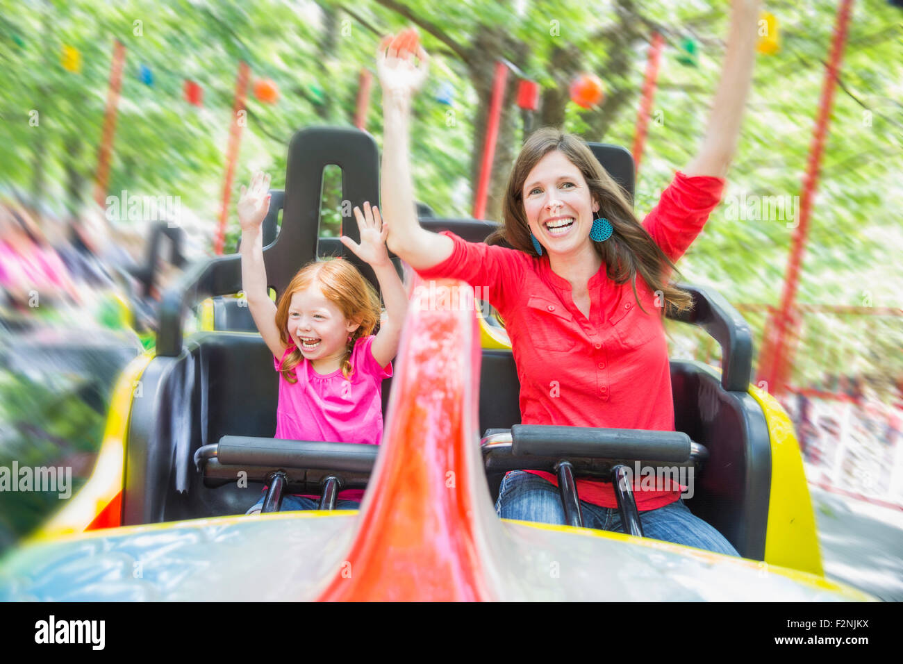 Mother and daughter riding roller coaster in amusement park Stock Photo ...